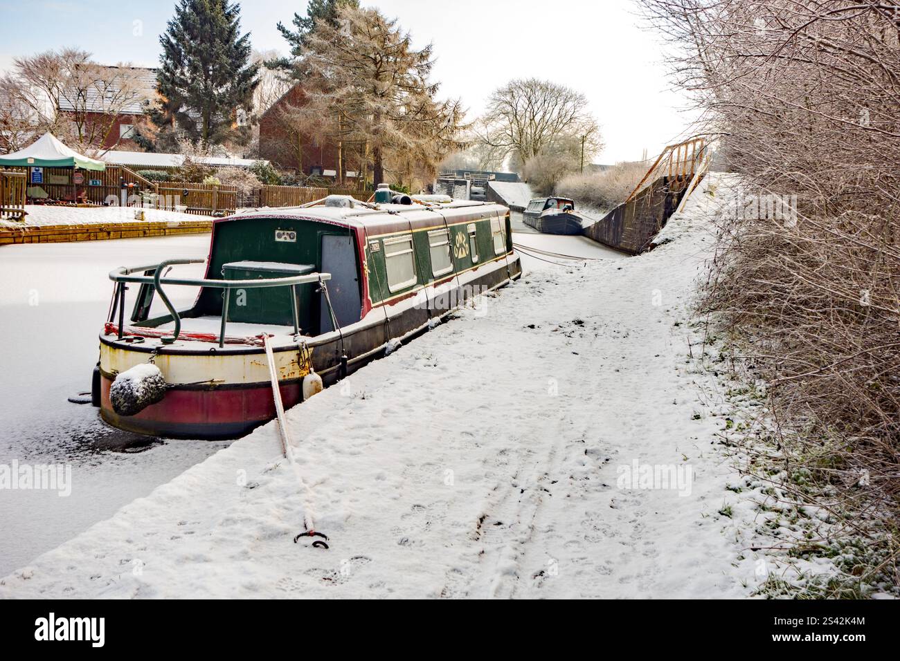 Canal narrowboat frozen in an iced up snow covered winter landscape of ...
