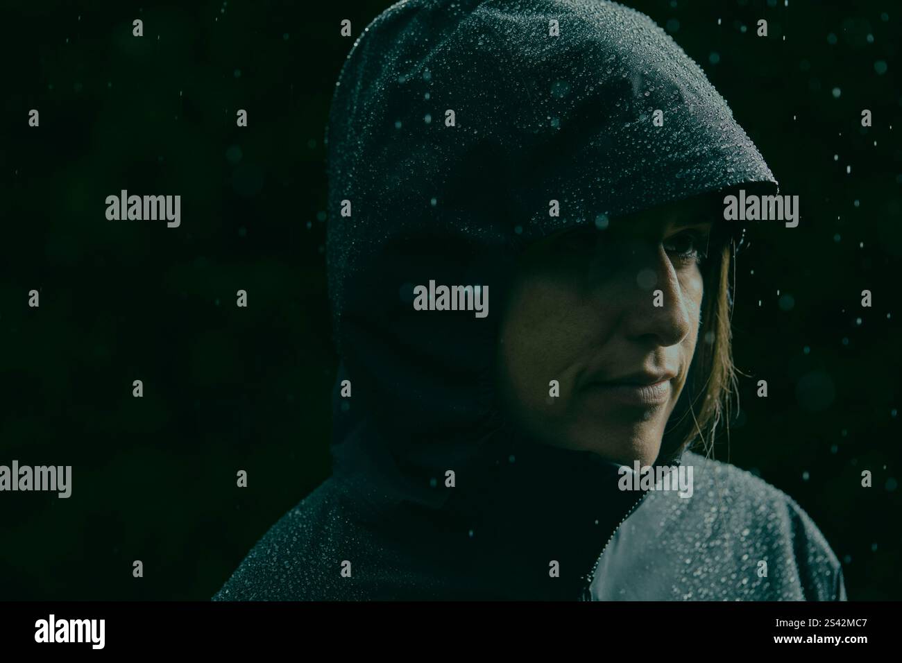 Person in a hooded rain jacket with water droplets, standing in rain ...