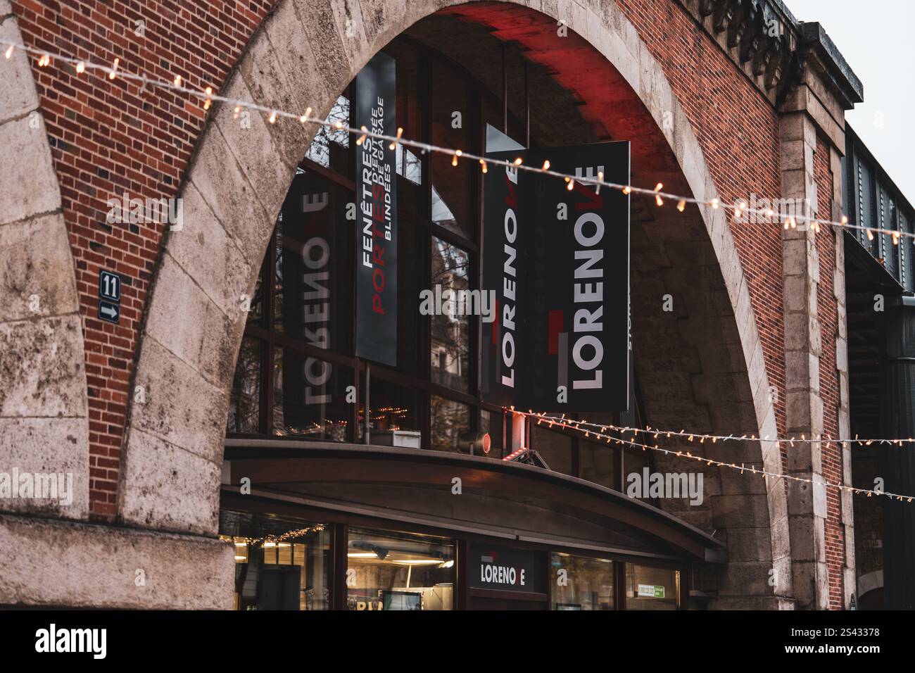 Urban market located under a historical arch with festive string lights ...