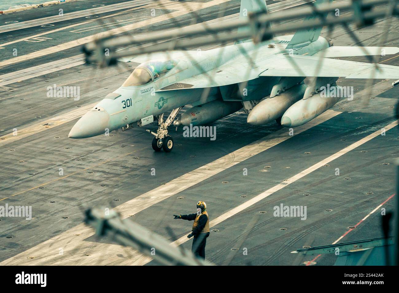 250109-N-EE352-1102 SOUTH CHINA SEA (Jan. 9, 2025) A Sailor directs an F/A-18E Super Hornet ...