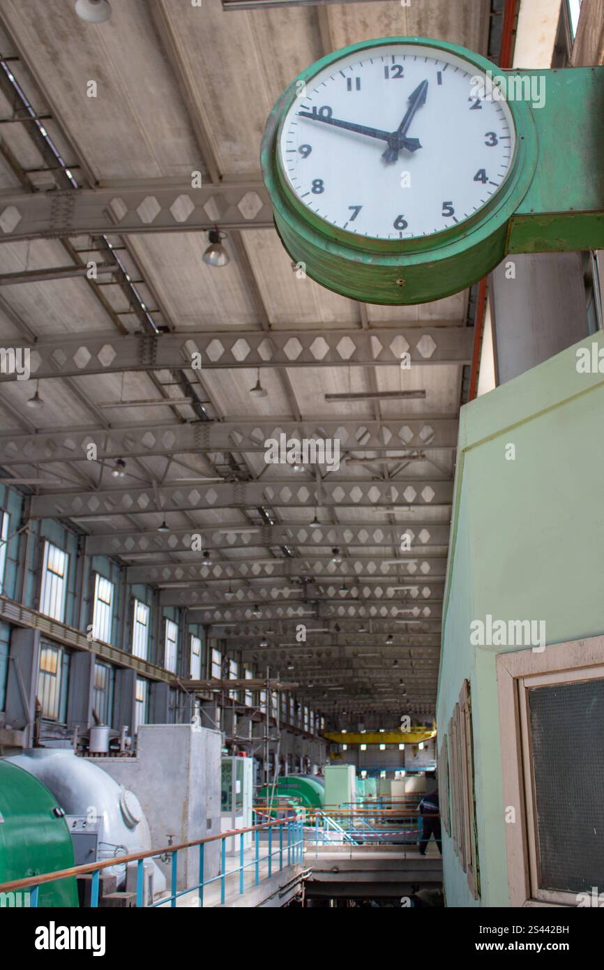 An industrial clock pointing at ten to one. Inside an old oil powered ...