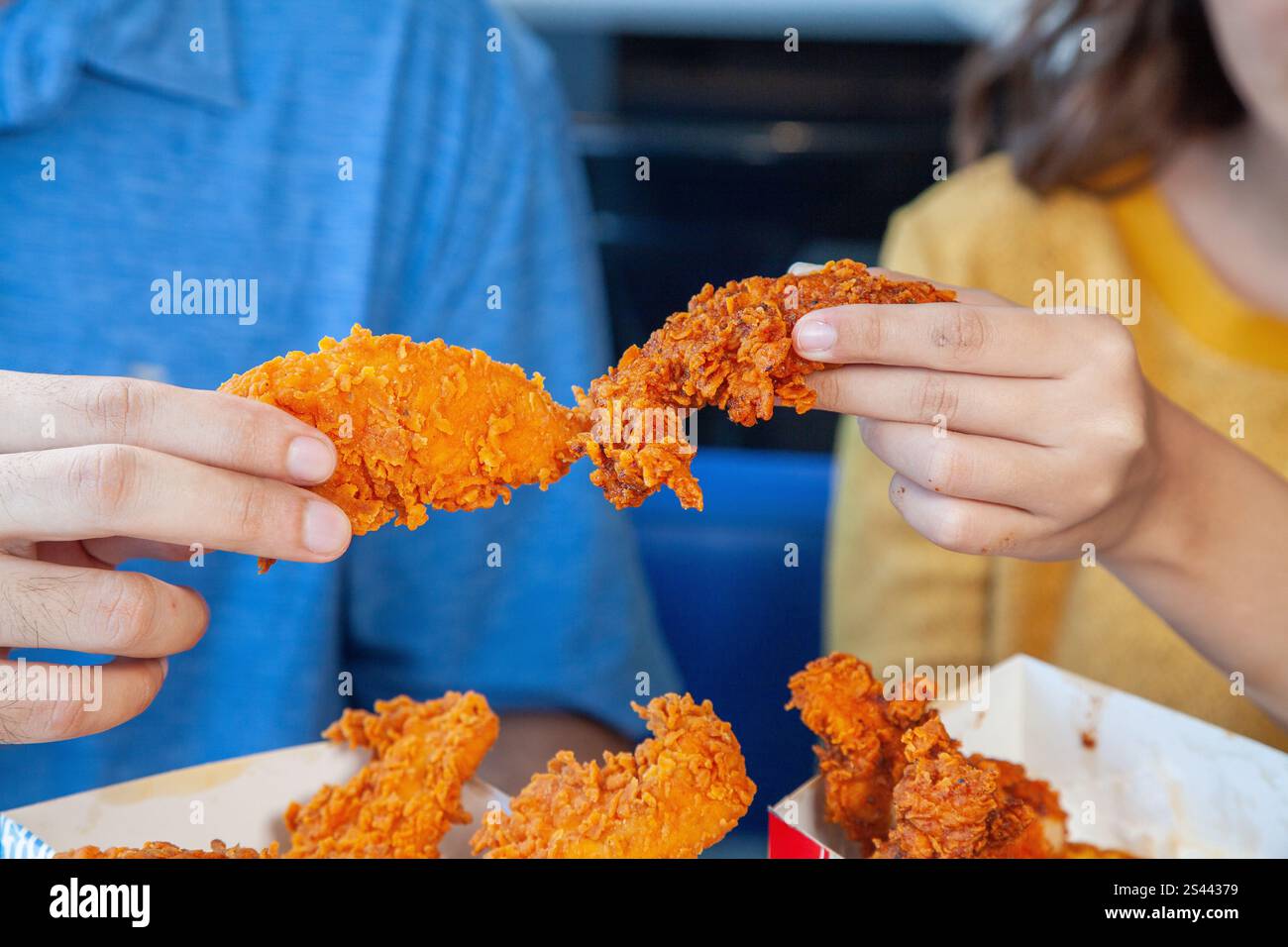 Boy and girl cheering on chicken strip in a cafe environment lifestyle ...