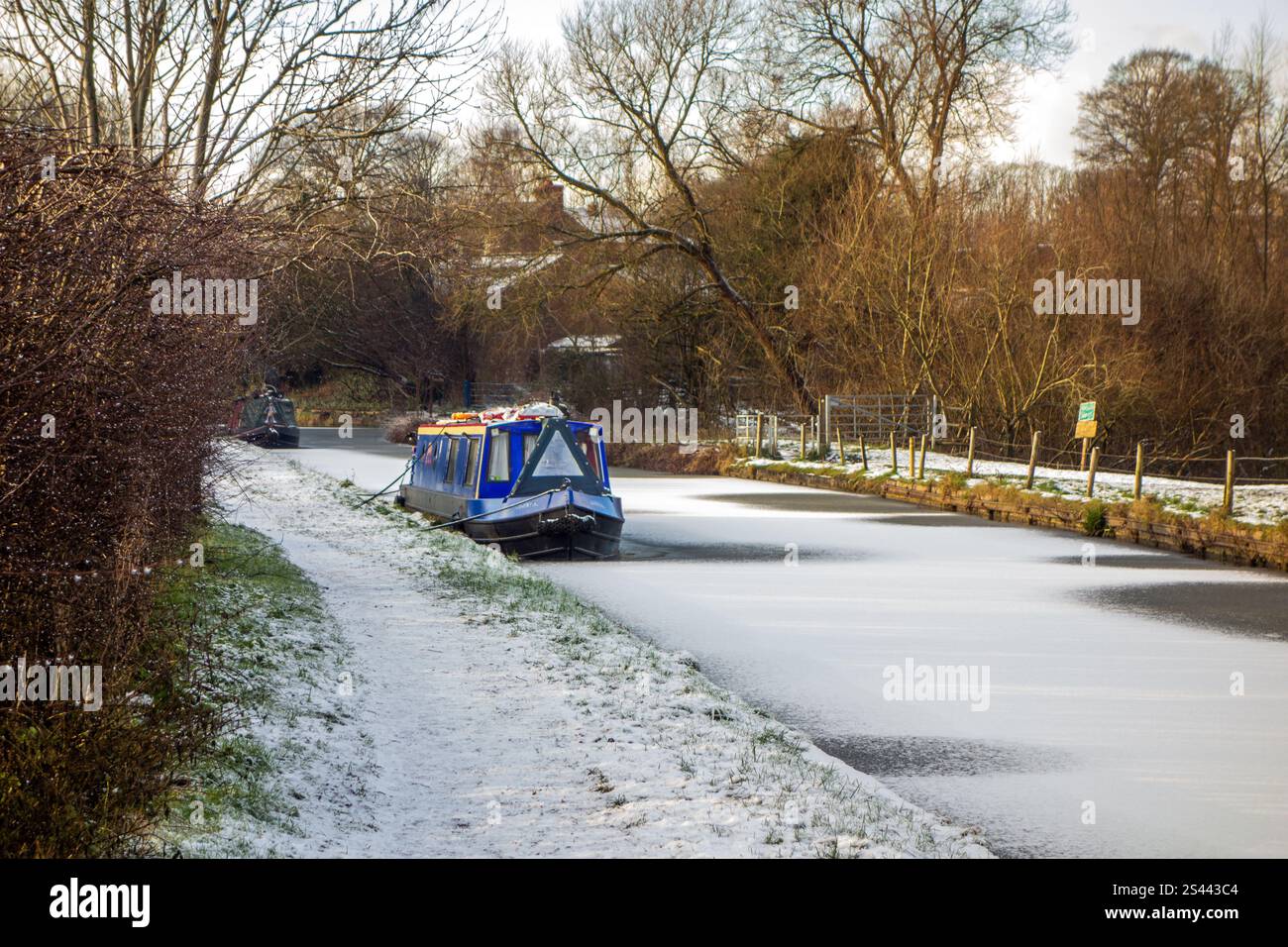Canal narrowboat frozen in an iced up snow covered winter landscape of ...