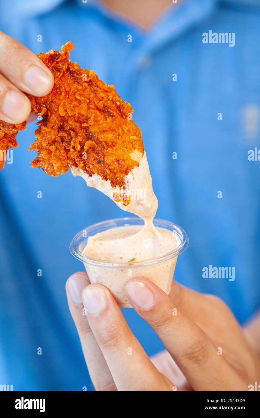 Man holding fried chicken strip dunking in spicy mayo sauce Stock Photo ...