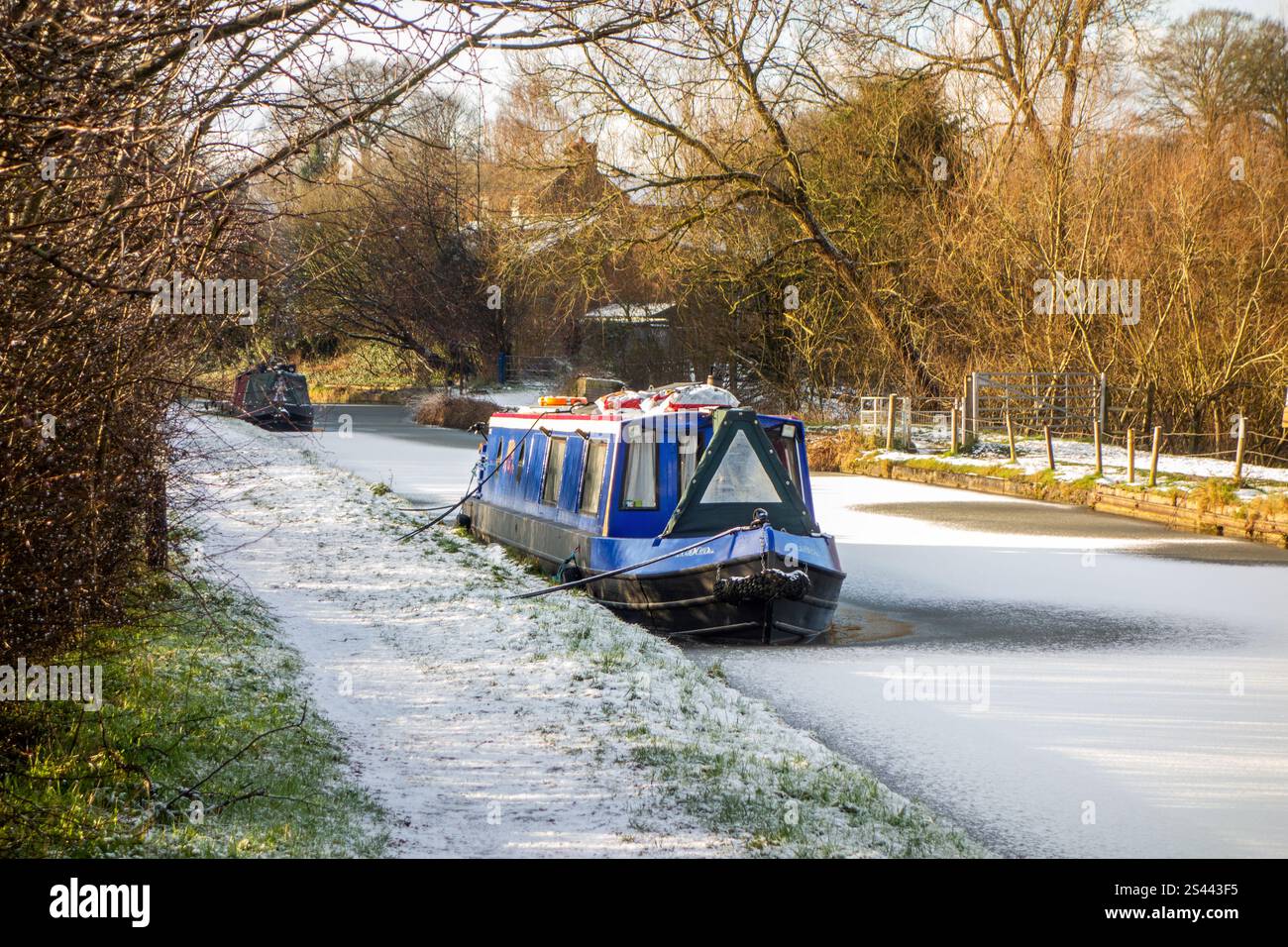 Canal narrowboat frozen in an iced up snow covered winter landscape of ...
