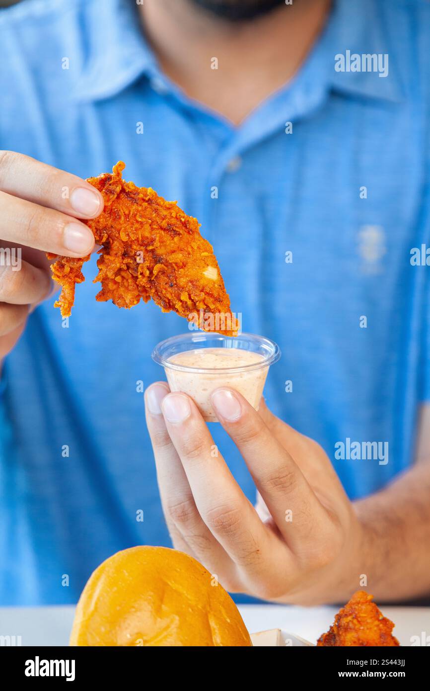 Man holding fried chicken strip dunking in spicy mayo sauce Stock Photo ...