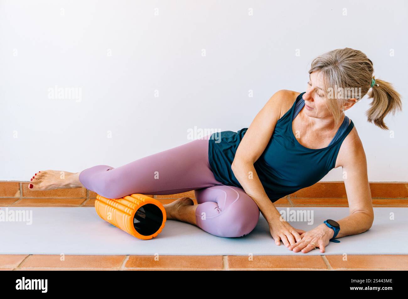 Woman doing self myofascial release of inner thigh with foam roller ...