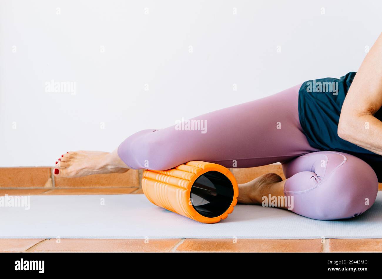 Woman doing self myofascial release of inner thigh with foam roller ...