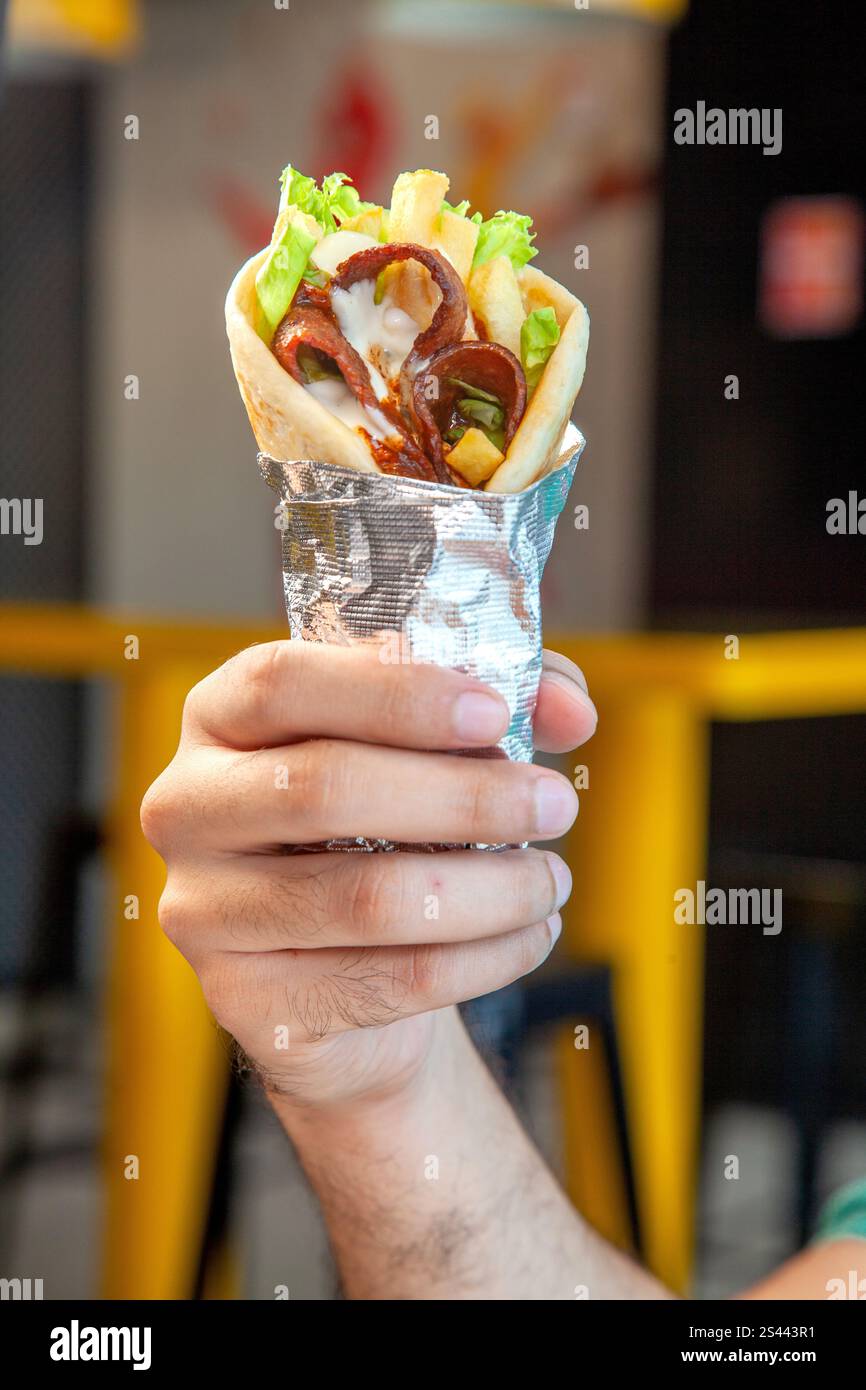 Prime beef thinly sliced doner wrap in pita bread holding in male hand ...