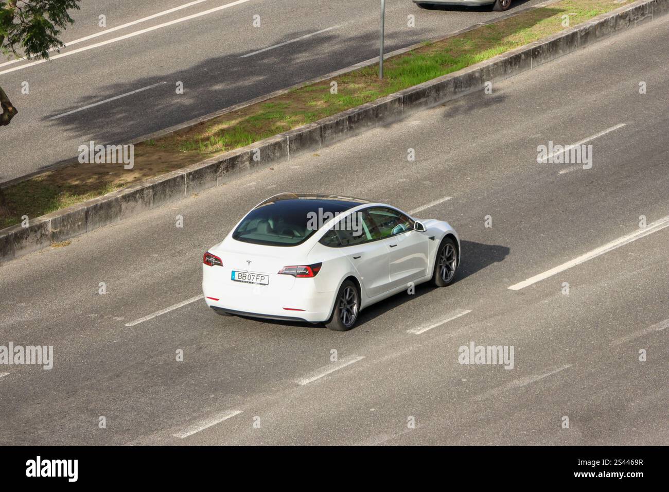 White tesla model 3 electric car driving on highway in urban setting ...