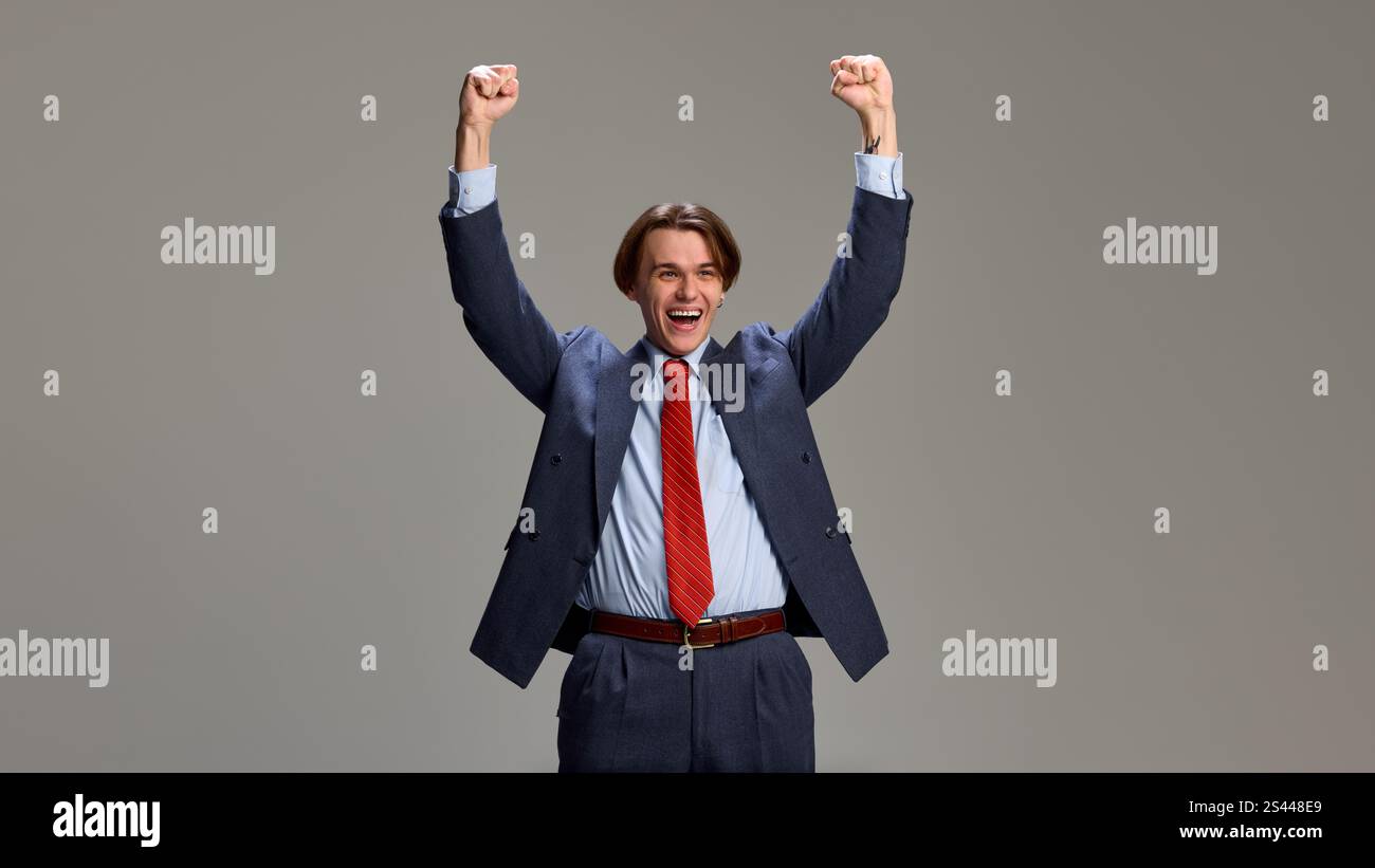 Celebrating with arms raised triumphantly, man in suit beams with ...
