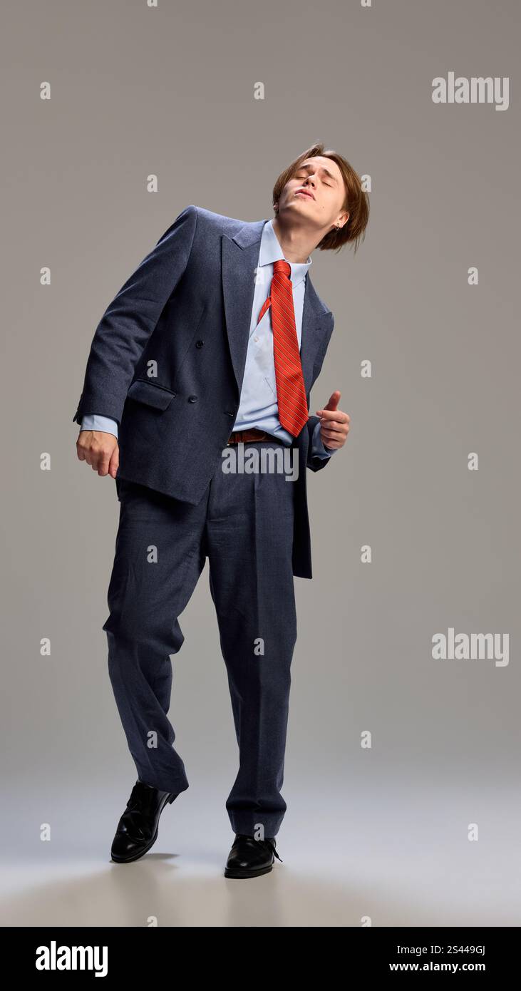 Confident, relaxed young man dancing, dressed formal attire and red tie ...