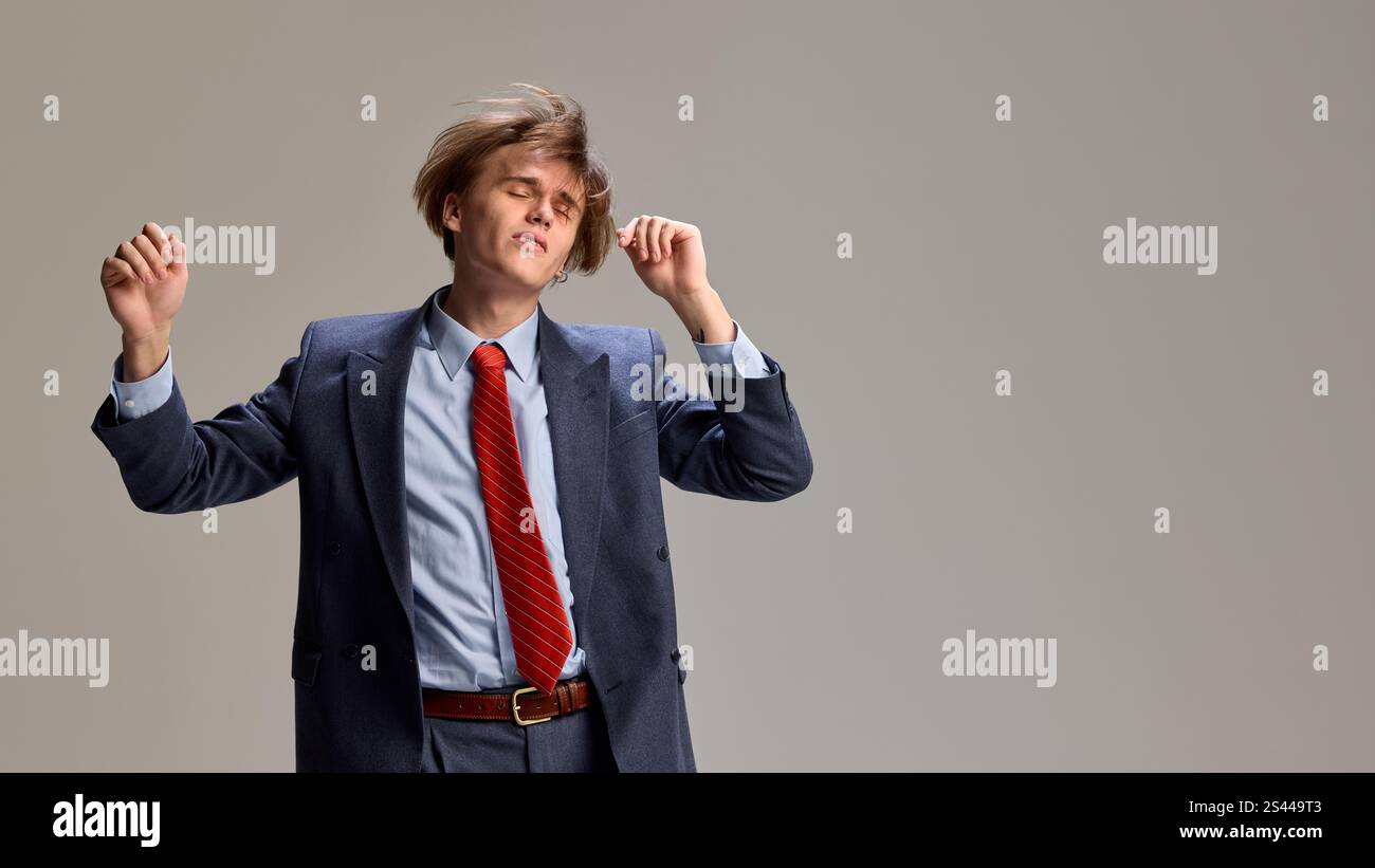 Man in suit and tie dancing with closed eyes, arms raised in carefree ...