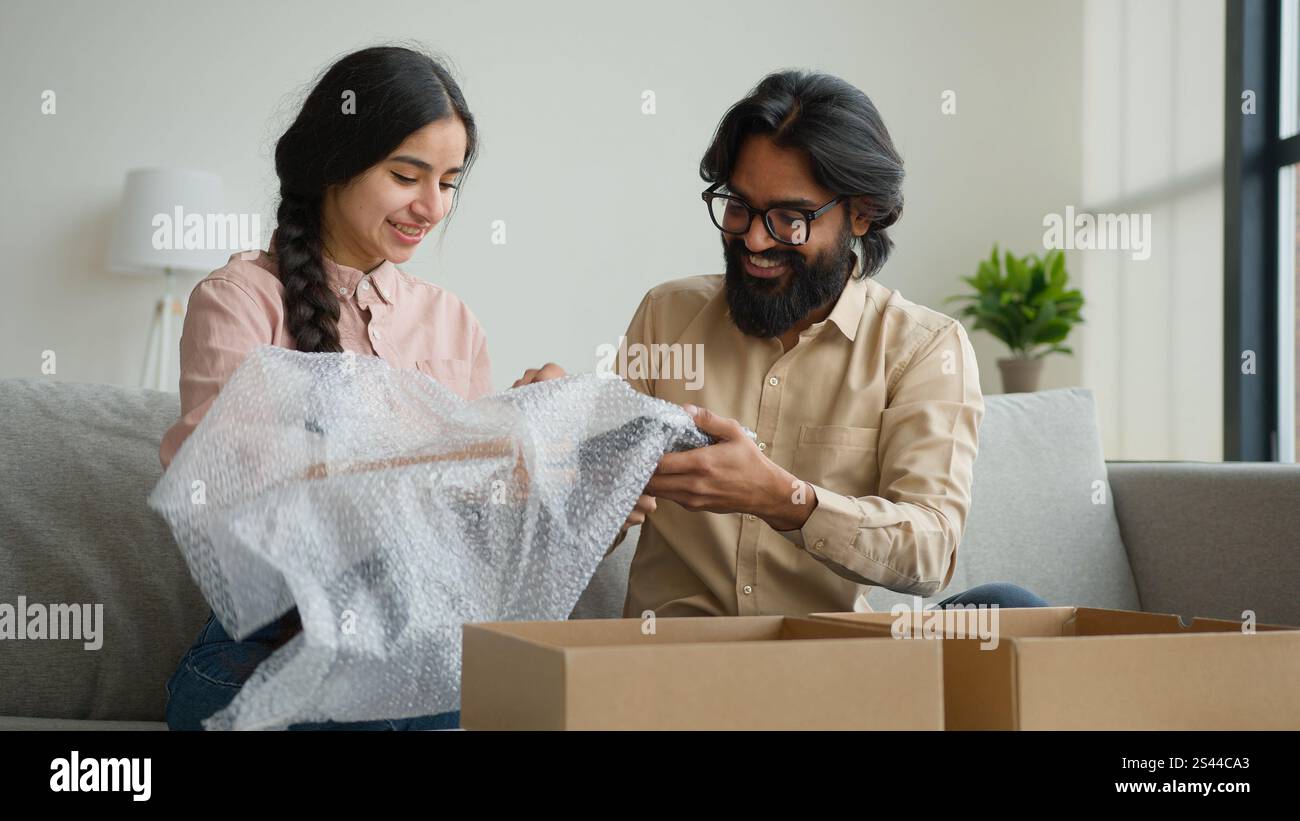 Happy couple customers receive parcel look inside box Arabian Indian man and woman open delivery ...