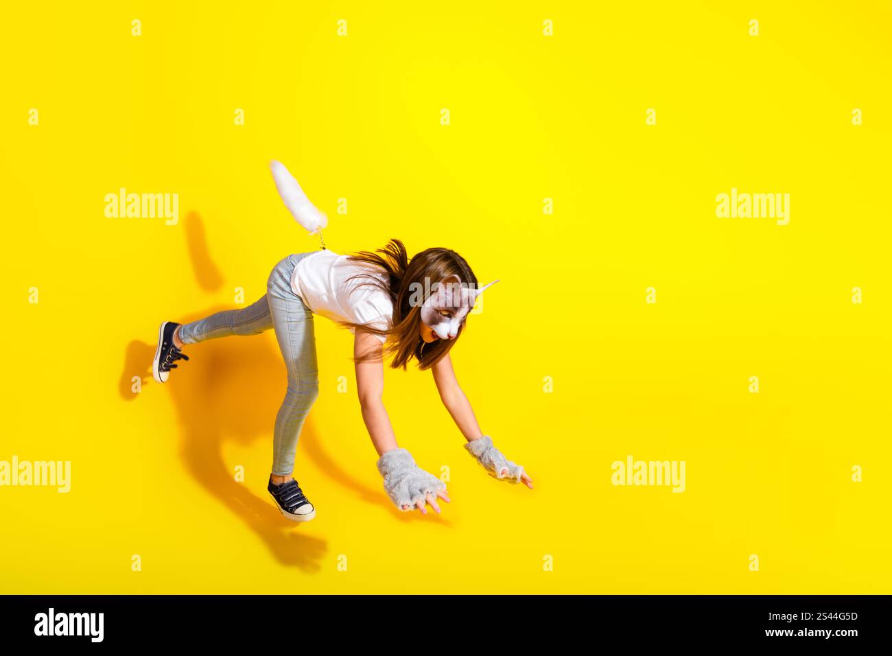 Young girl in animal-themed costume posing on a bright yellow colored ...