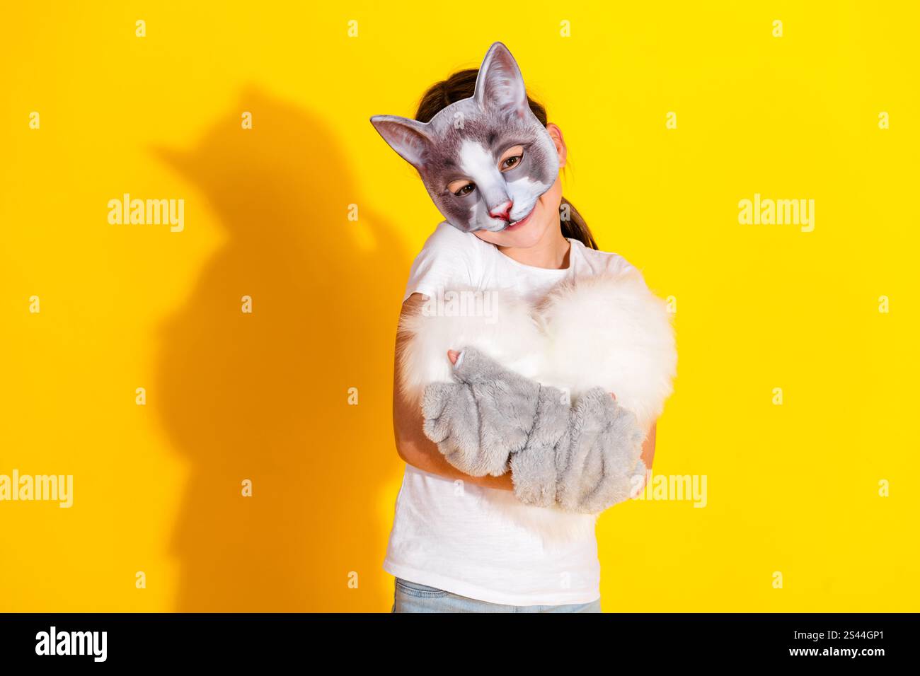 Young girl wearing a cat mask and fluffy gloves posing against a ...