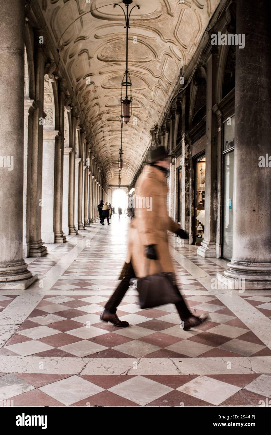 Man walking under arches in Venice Stock Photo - Alamy
