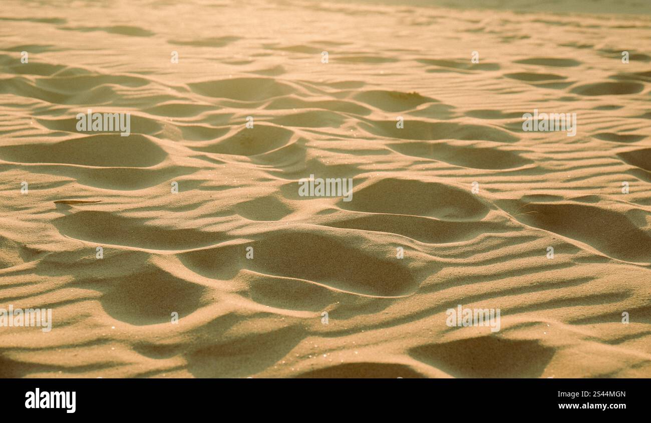 Sand in sunset light with traces of human feet Stock Photo - Alamy