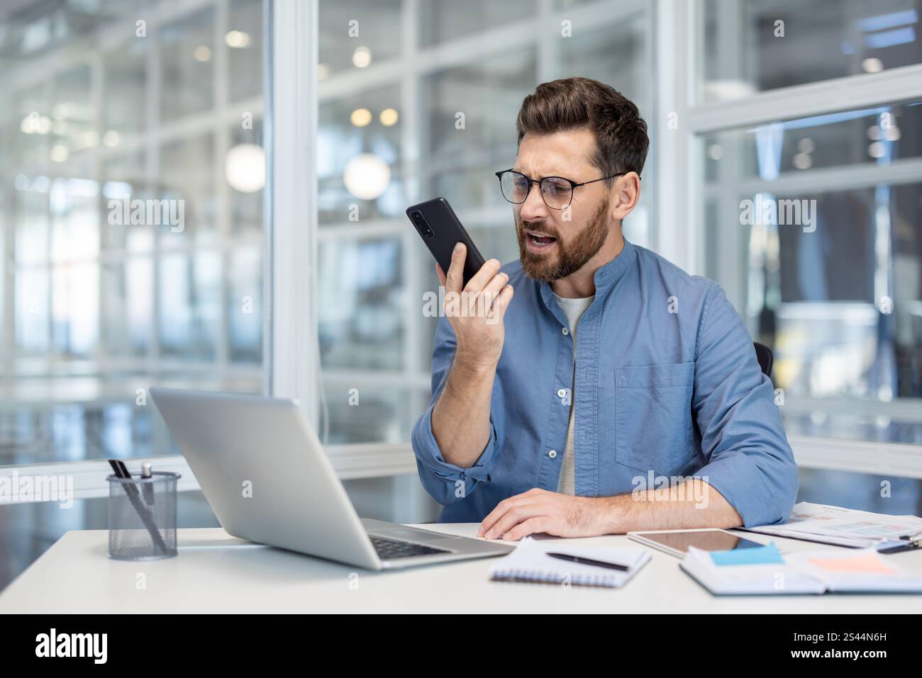 Angry and furious man shouting into phone, office worker working at ...