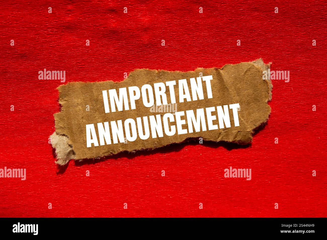 Important announcement message written on ripped torn cardbaord paper piece with red background ...