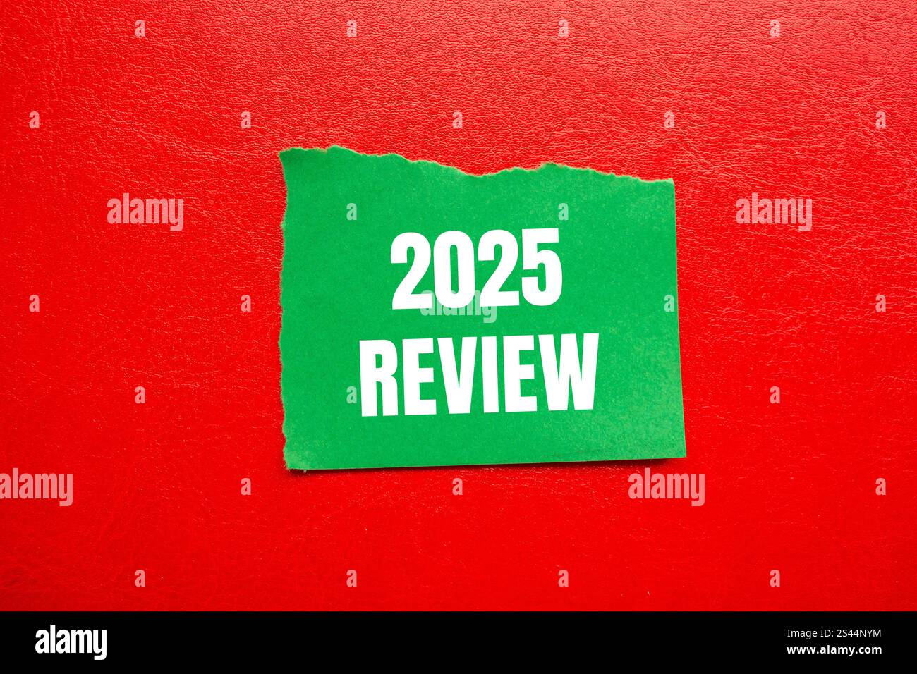 2025 review message written on ripped torn green paper piece with red background. Conceptual ...