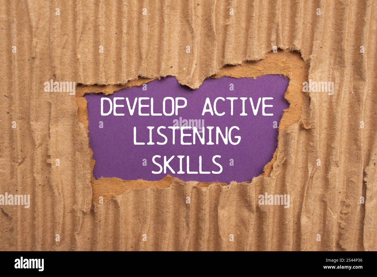 Develop active listening skills message written on ripped torn cardboard paper with purple ...