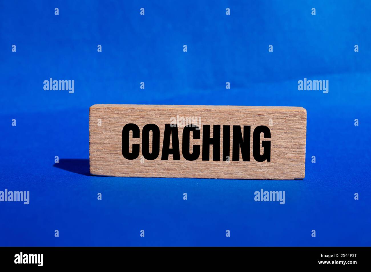 Coaching message written on wooden block with blue background ...