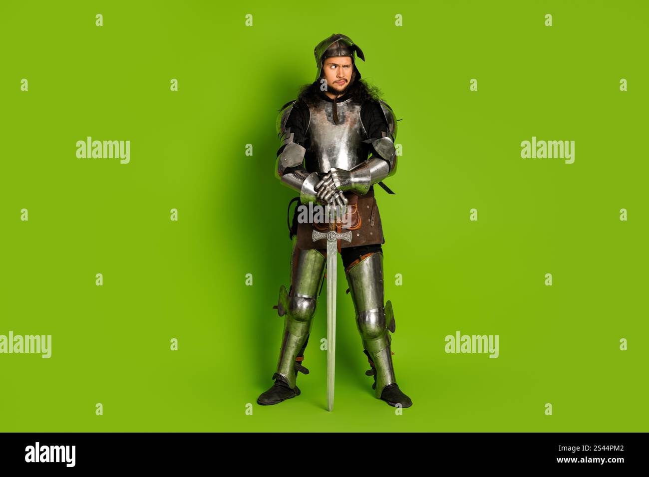 Portrait of a young knight in steel armor posing with a sword on a ...