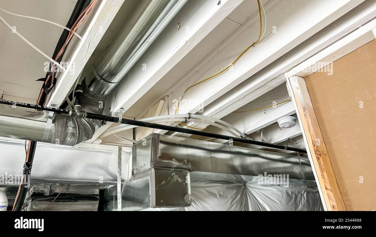 Exposed ductwork and plumbing in new construction basement Stock Photo ...