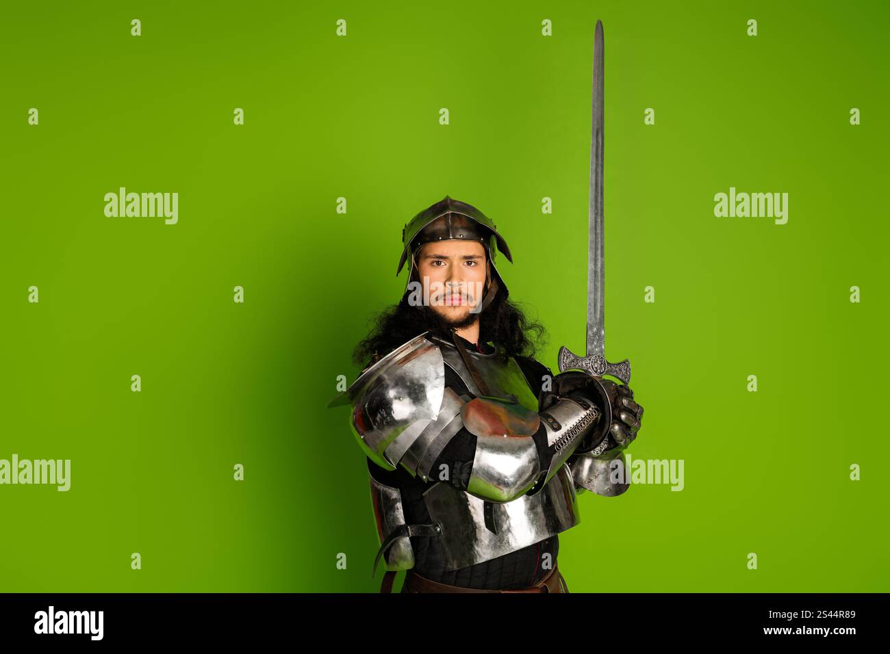 Medieval knight in shiny armor holding a sword on green background portraying historical bravery ...