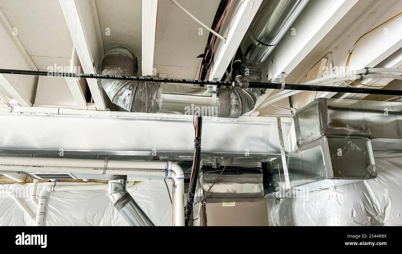 Exposed ductwork and plumbing in new construction basement Stock Photo ...