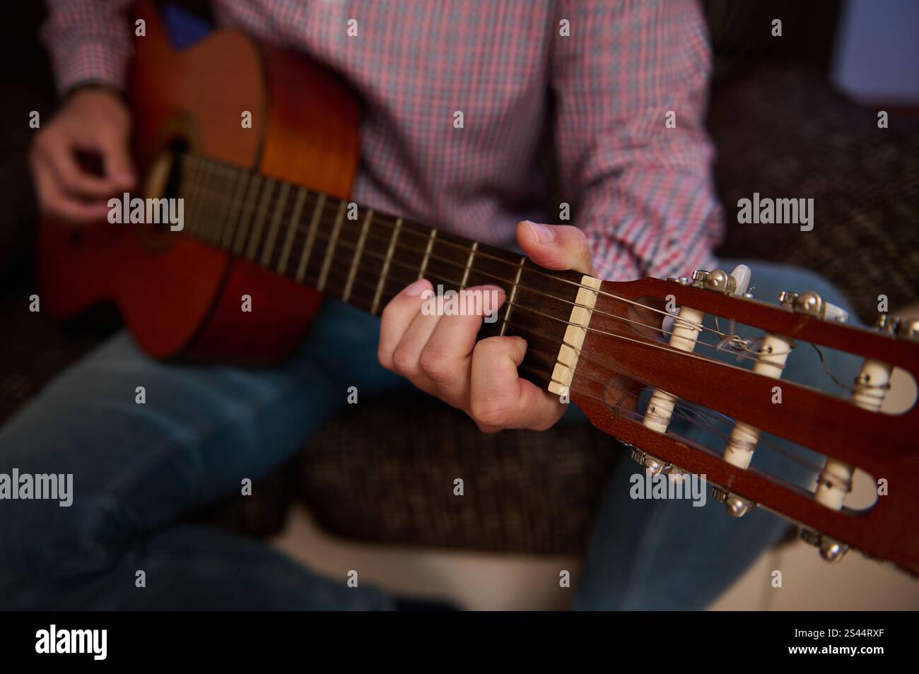 A person is playing an acoustic guitar, seated with a relaxed posture ...