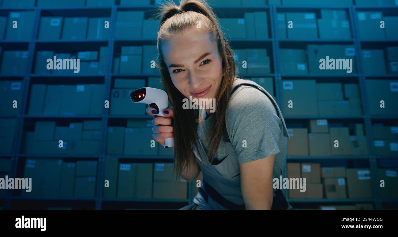 Positive Female Warehouse Worker Looking at Camera, Scanning Cardboard ...