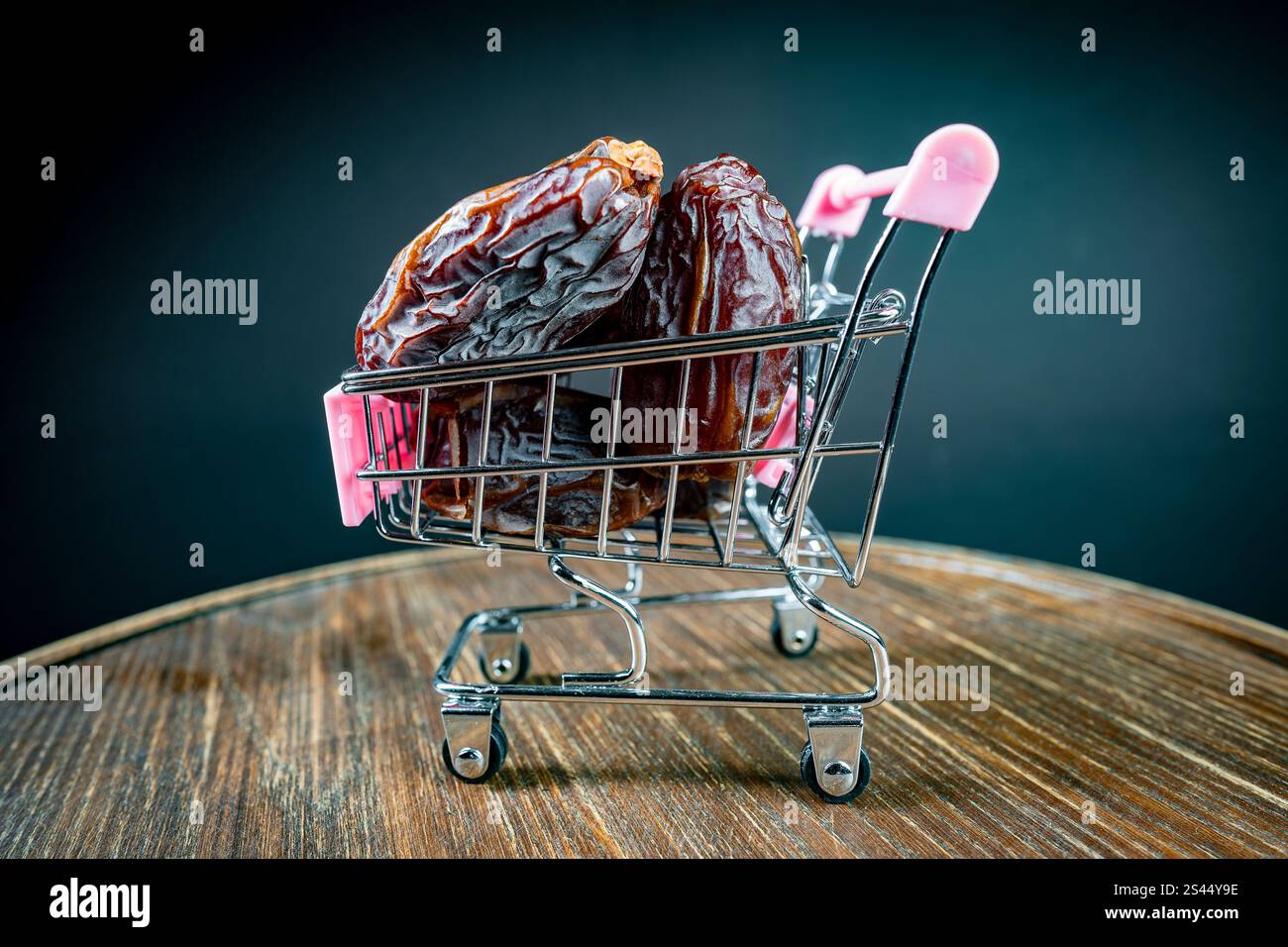 Shopping cart on wheels with dates fruit on dark background, close up ...