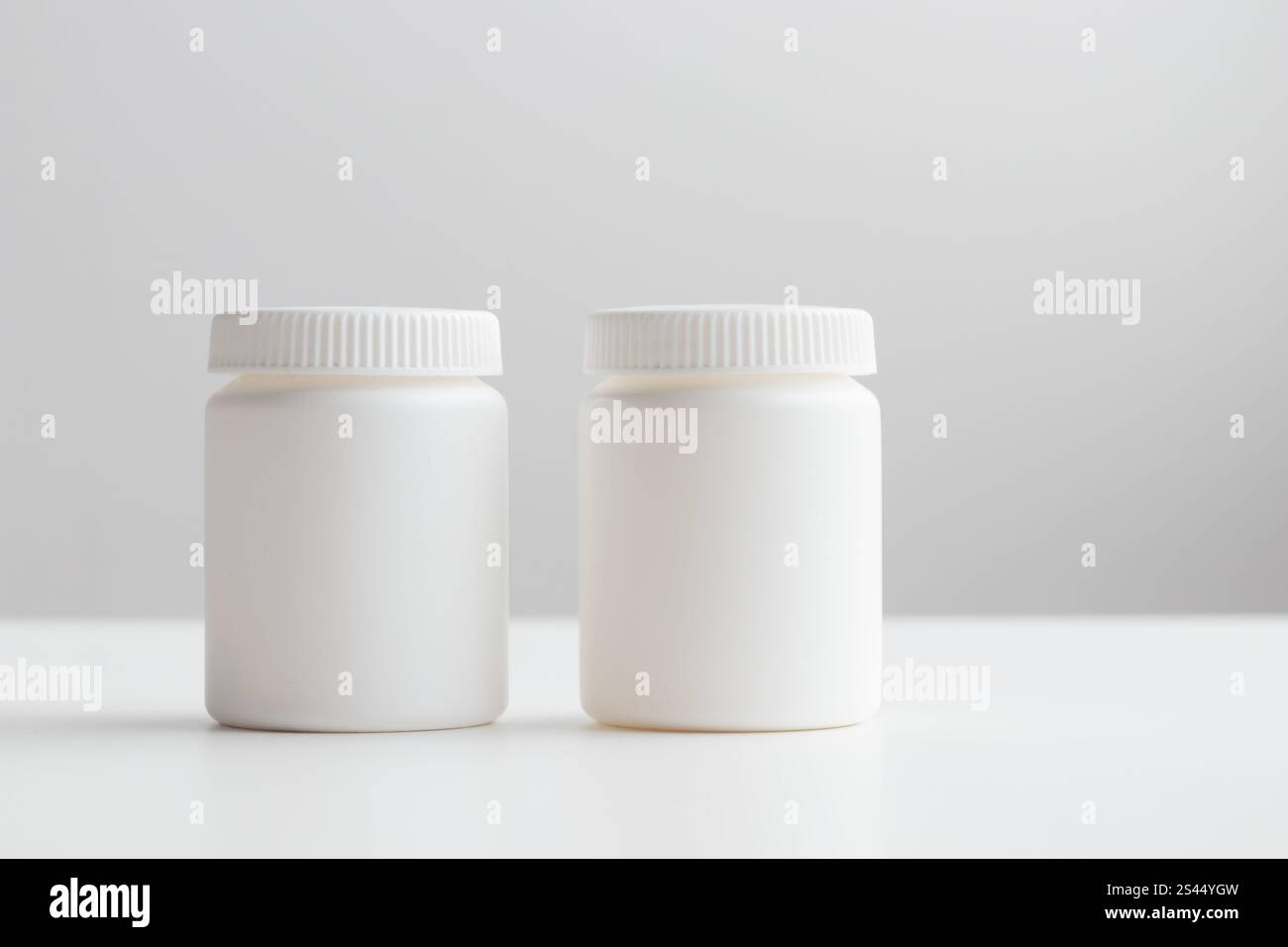Two blank white vitamin bottles. Unlabeled white nutritional supplement ...