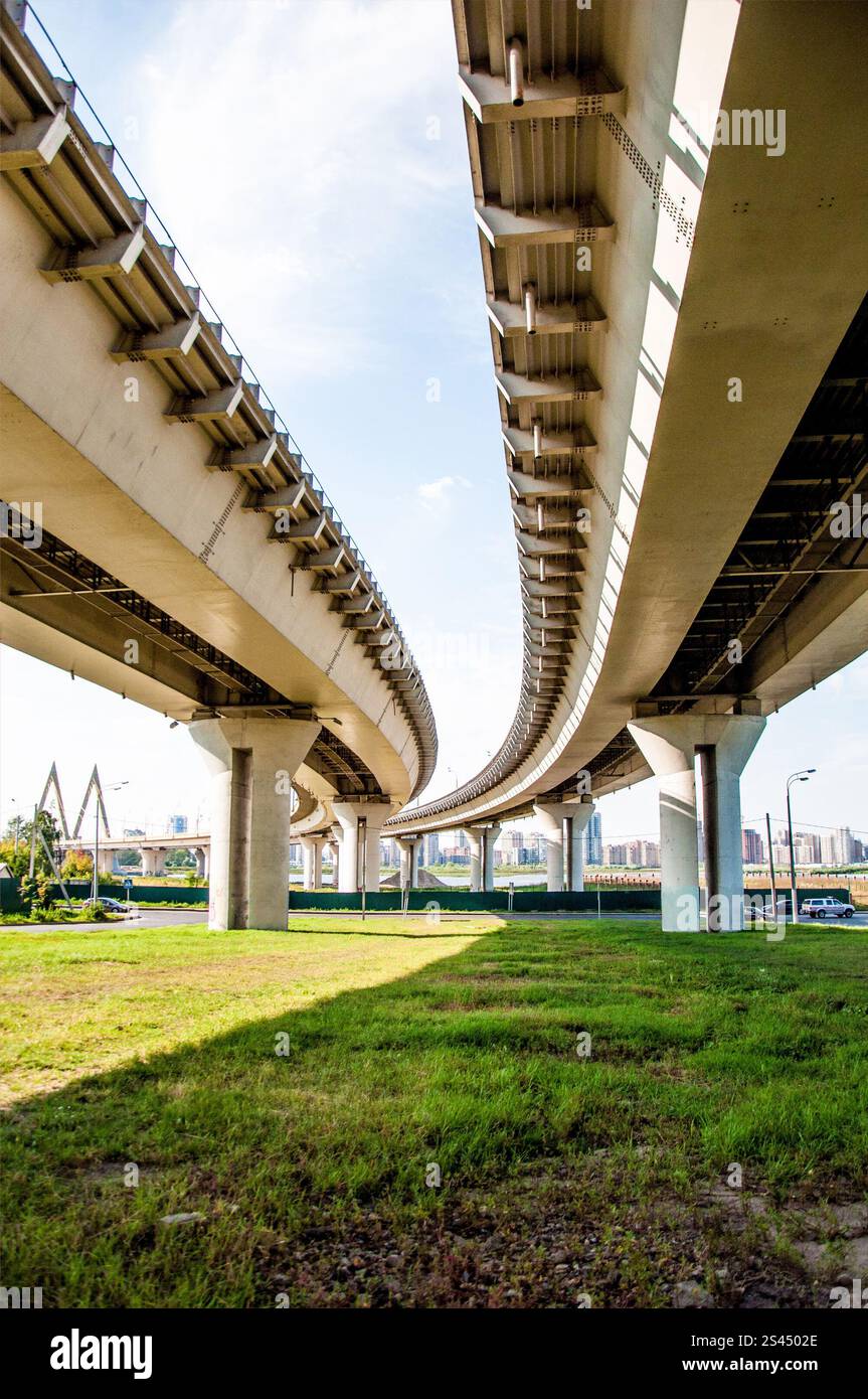 View under the bridge over the river, cityscape, bright day and green ...