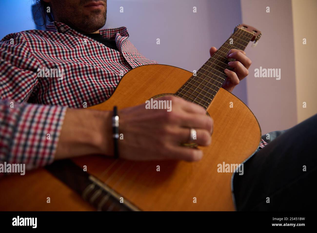 A close-up view of someone playing an acoustic guitar while seated ...