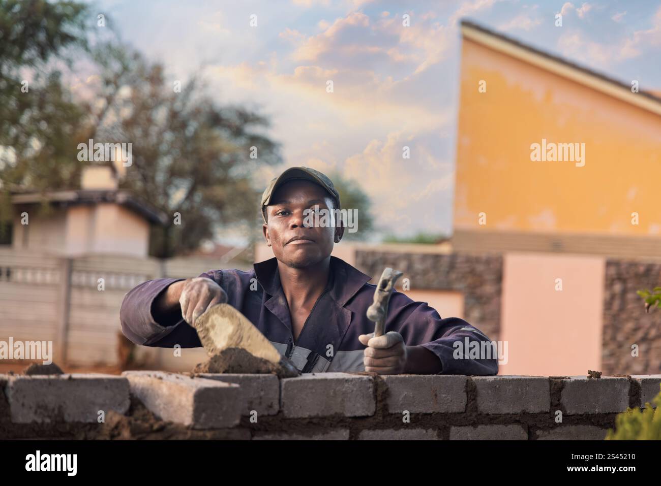 bricklayer african men, using a trowel and a hammer, building a wall at ...