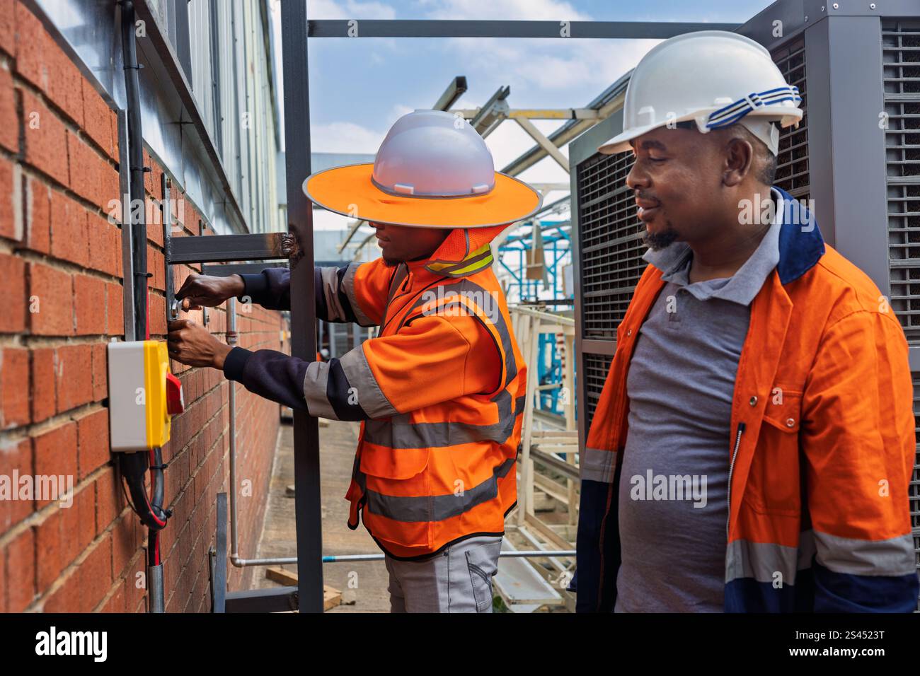 african american workers colleagues, repairing hvac unit, with orange ...