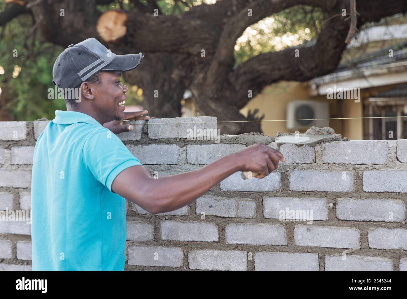 bricklayer african men, using a trowel and a string to align bricks ...