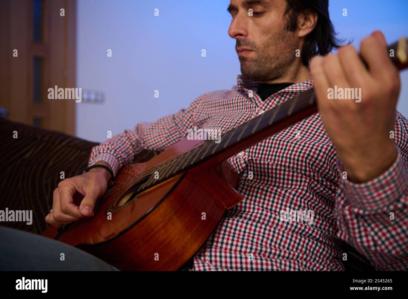 Person playing a wooden acoustic guitar, focusing on the strumming hand ...