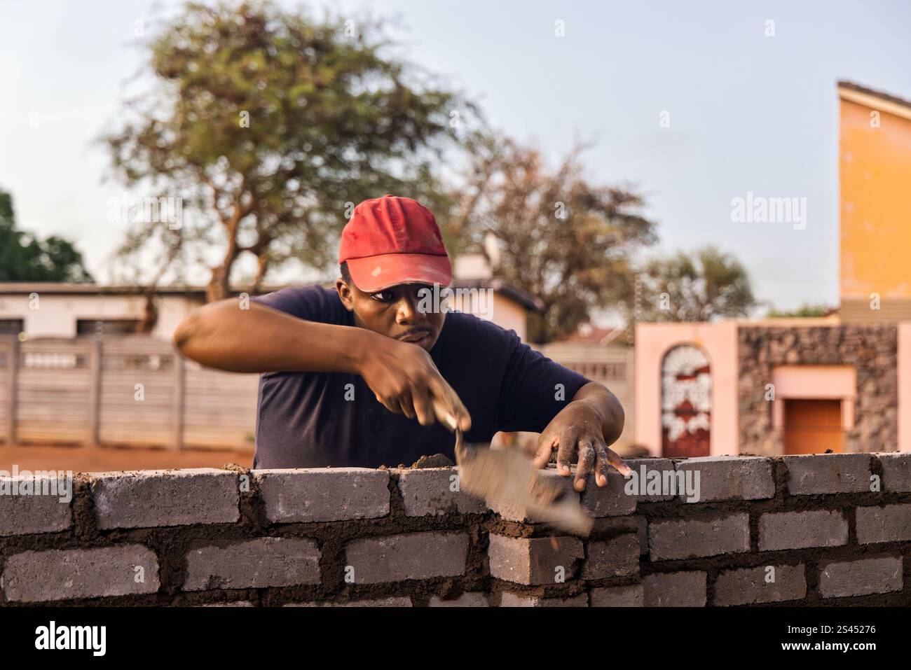 bricklayer african men , using a trowel and align string, building a ...