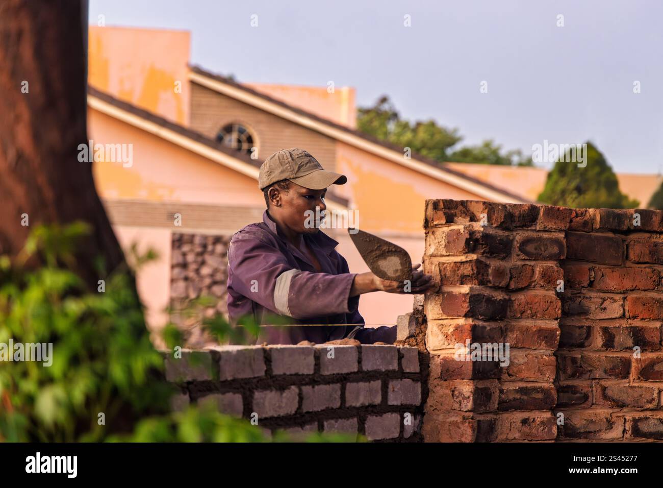 bricklayer african men , using a trowel and align string, building a ...