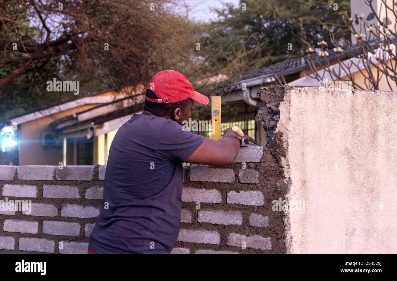 bricklayer african men alone, using a trowel and yellow bubble spirit ...