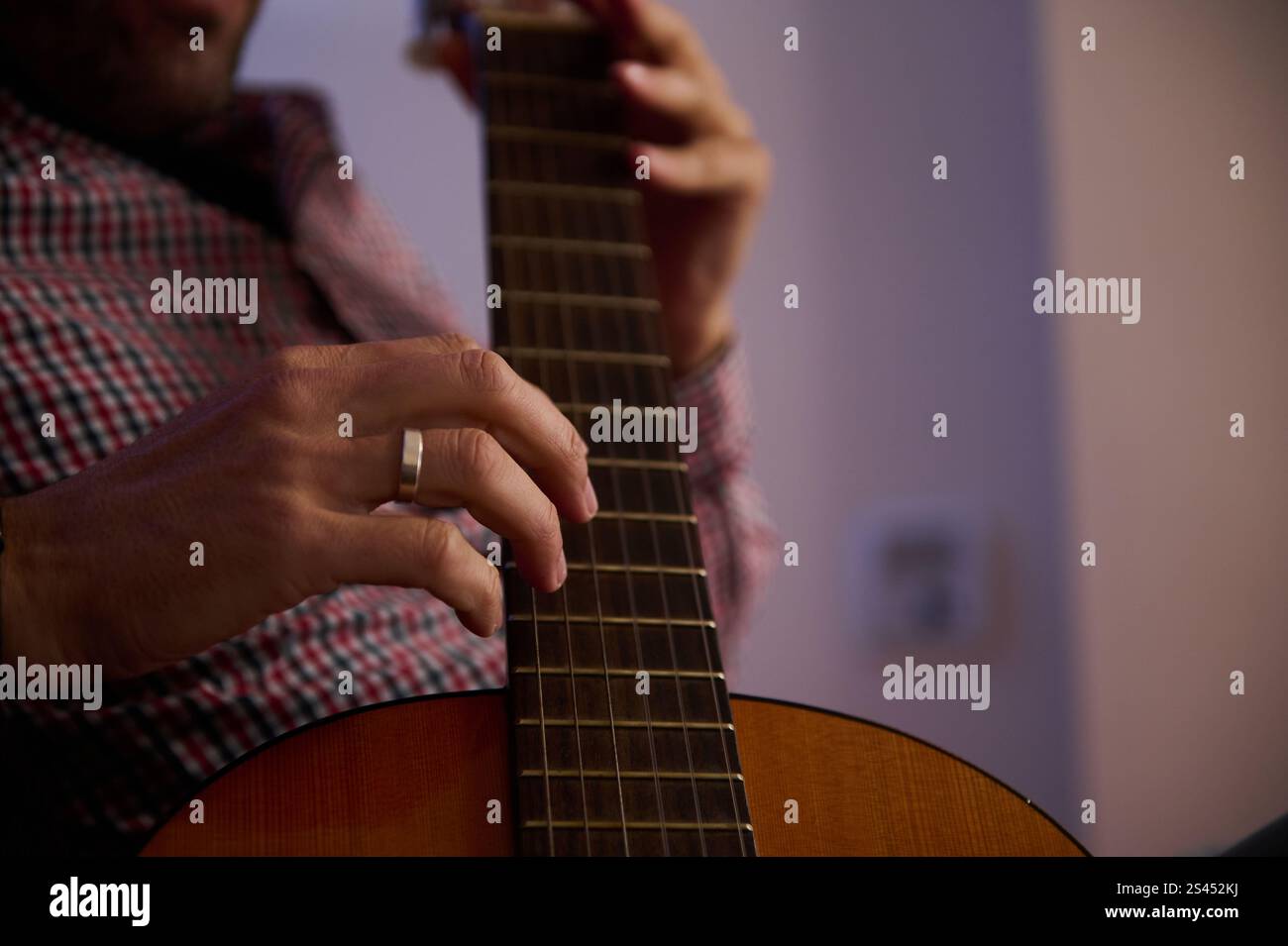 A detailed view of a musician's hands playing an acoustic guitar ...