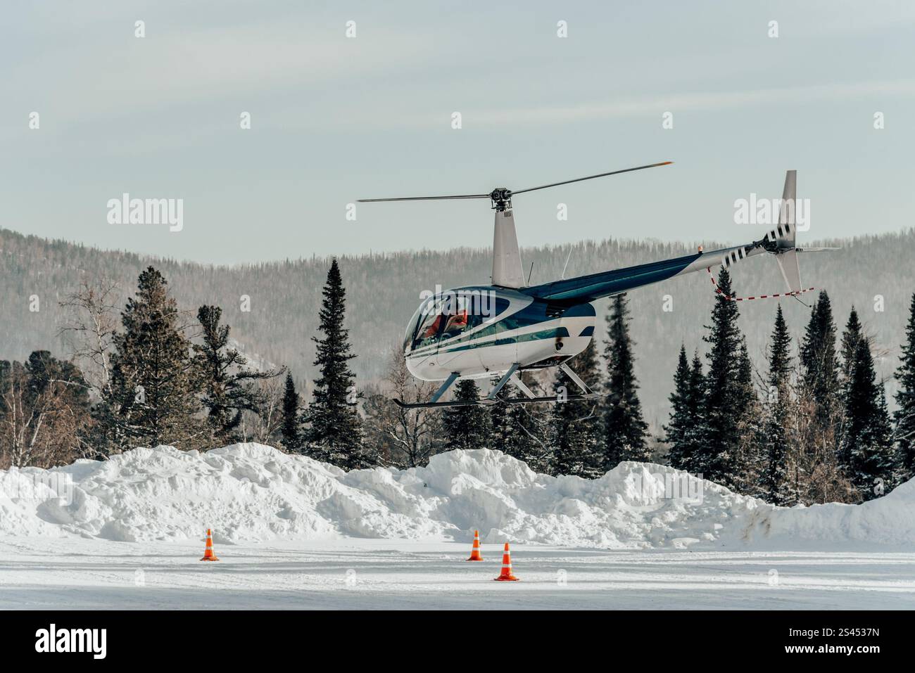 Tourist civilian small helicopter taking off, snowy winter mountain ...
