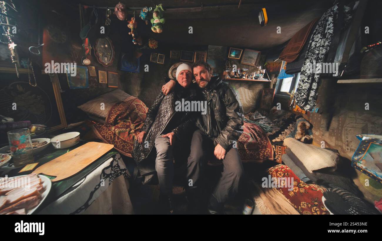 Alcohol addicted couple embracing on a bed in their messy, dilapidated ...