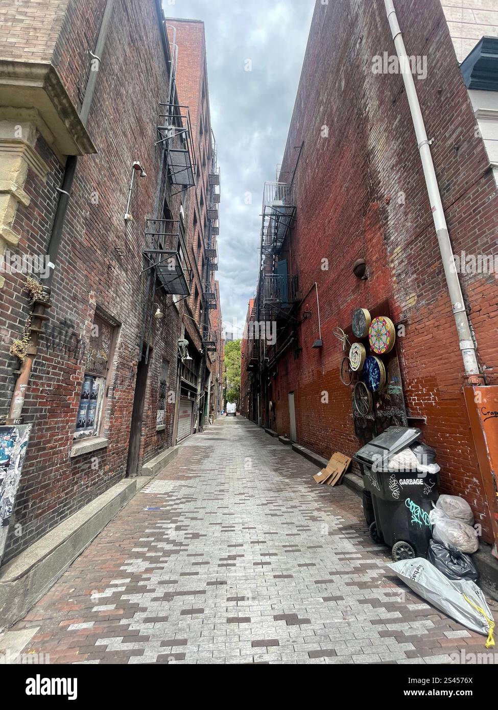 A narrow urban alleyway flanked by old red brick buildings Stock Photo ...