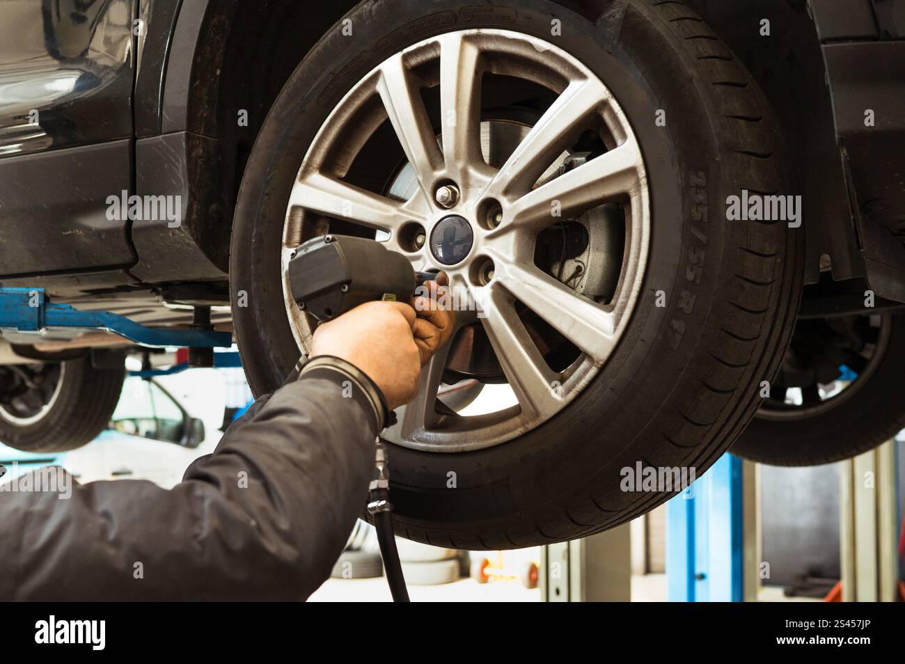 Mechanic using an impact wrench to change a car wheel in a professional ...