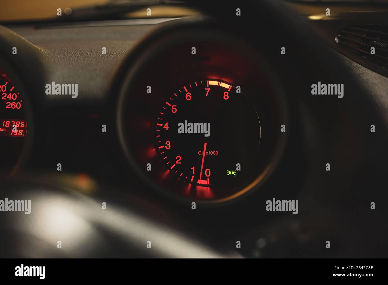 Car's round rev counter gauge illuminated at night. Close up shot ...